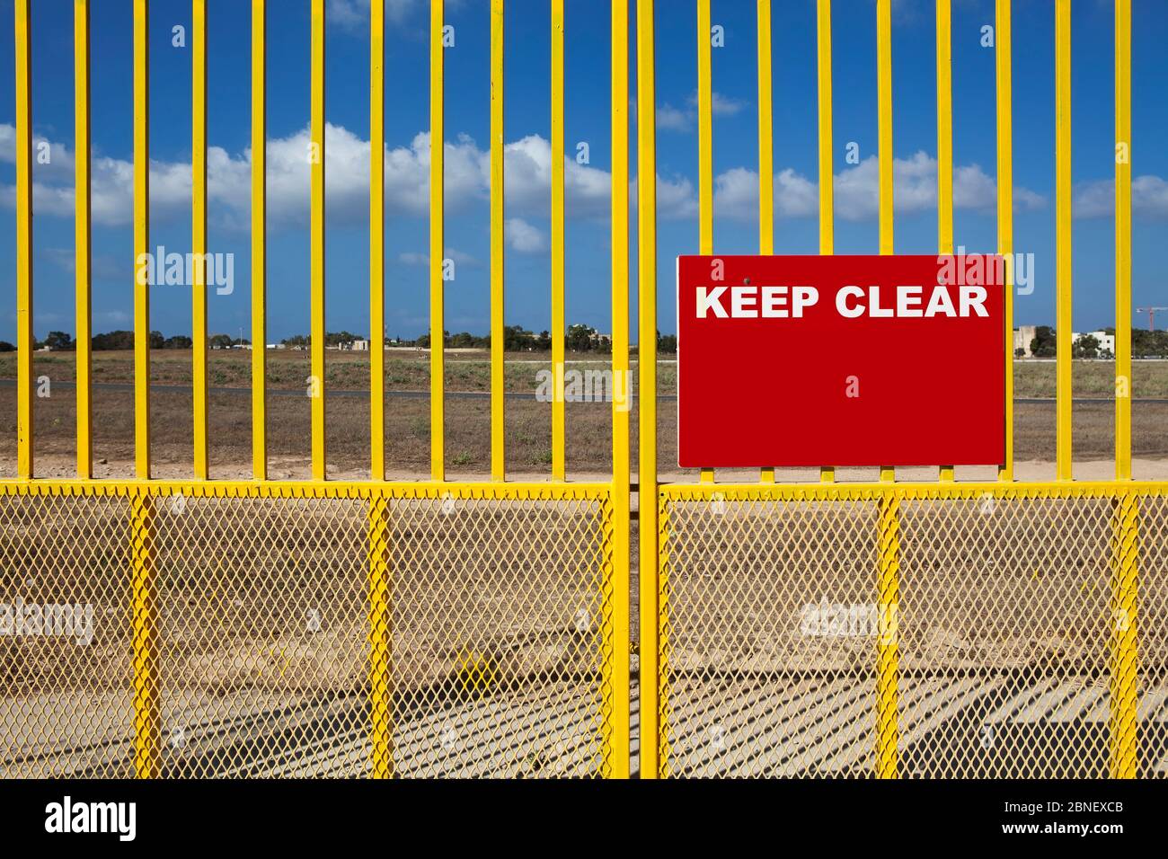 A red Keep Clear warning sign with copyspace on a bright yellow metal ...