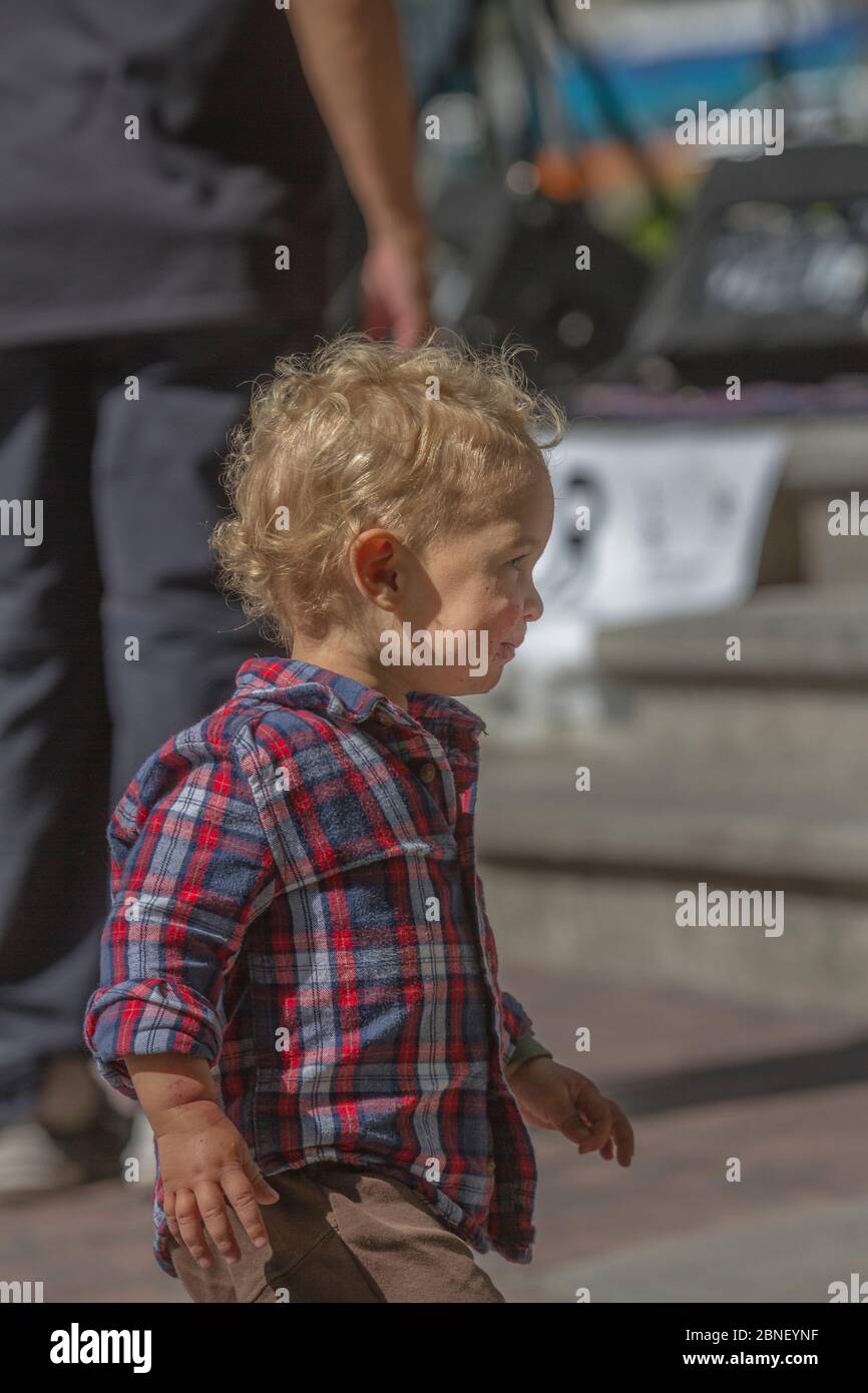 Cute shot of blonde, curly haired child, walking. Face is messy with ...