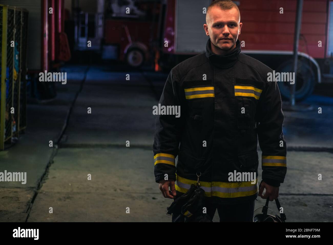 Portrait of young fireman standing inside the fire station Stock Photo ...