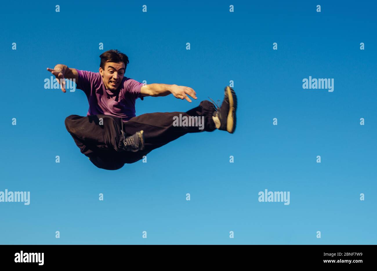 Young athletic man performing a flying kick move at the skatepark Stock ...