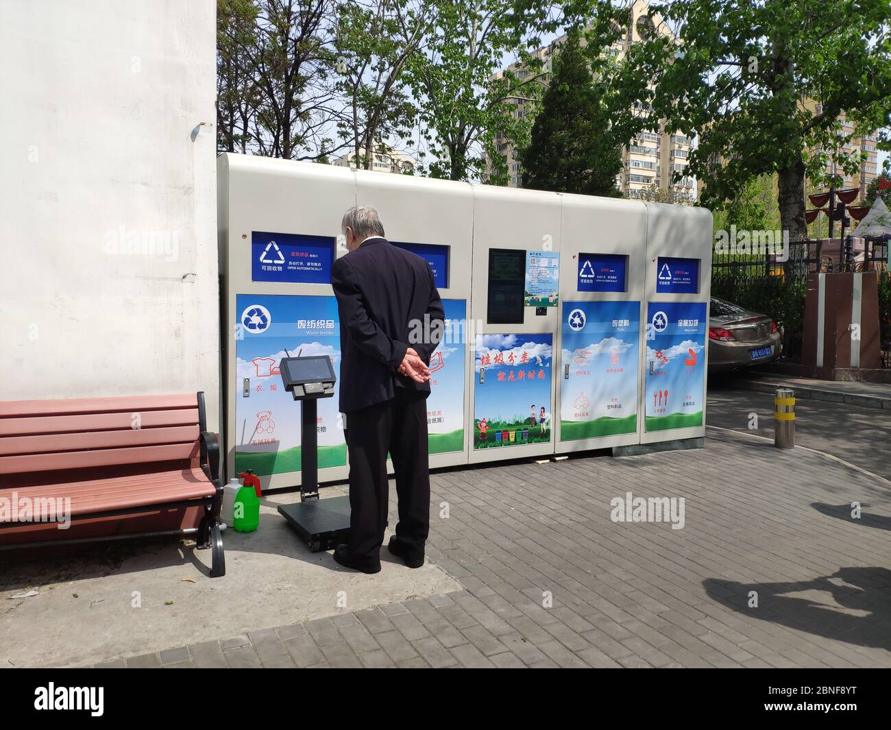 A resident looks at trash bins meeting the demand of new waste sorting ...