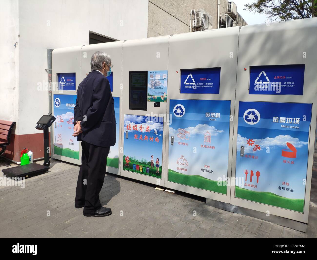 A resident looks at trash bins meeting the demand of new waste sorting ...