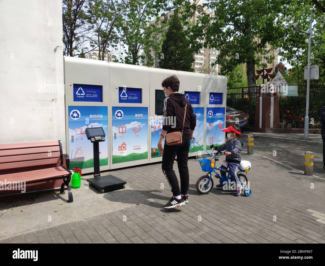 A resident looks at trash bins meeting the demand of new waste sorting ...