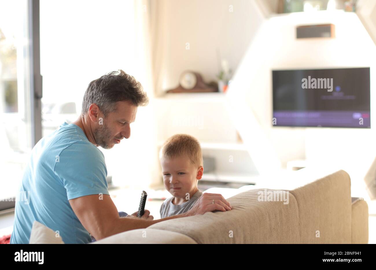 Father and his baby sun playing around and making funny faces sitting ...