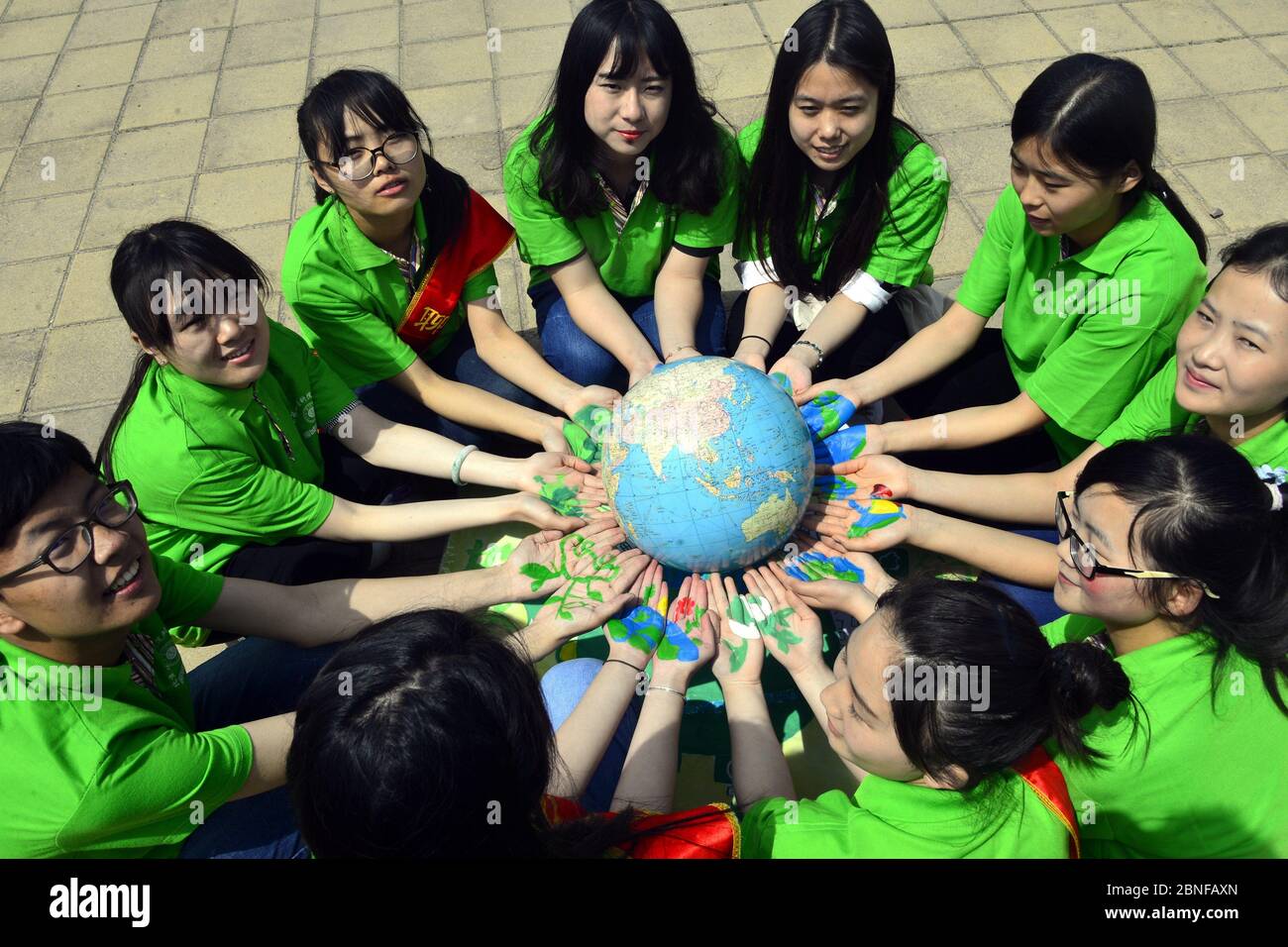 --FILE--A group of university students holds a globe with drawings ...