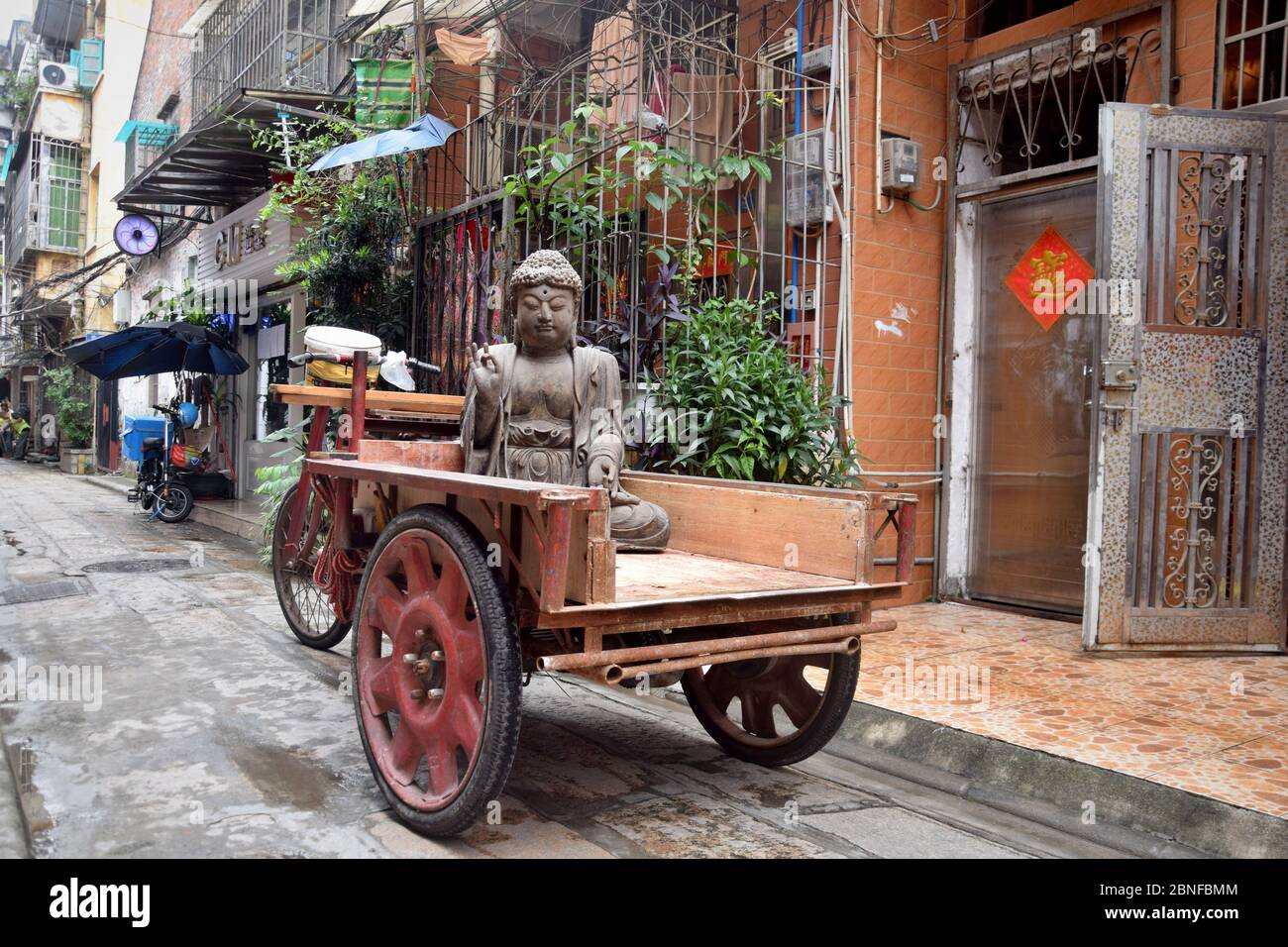A stone carved Buddha statue on a cart in an old alley of Guangzhou in ...