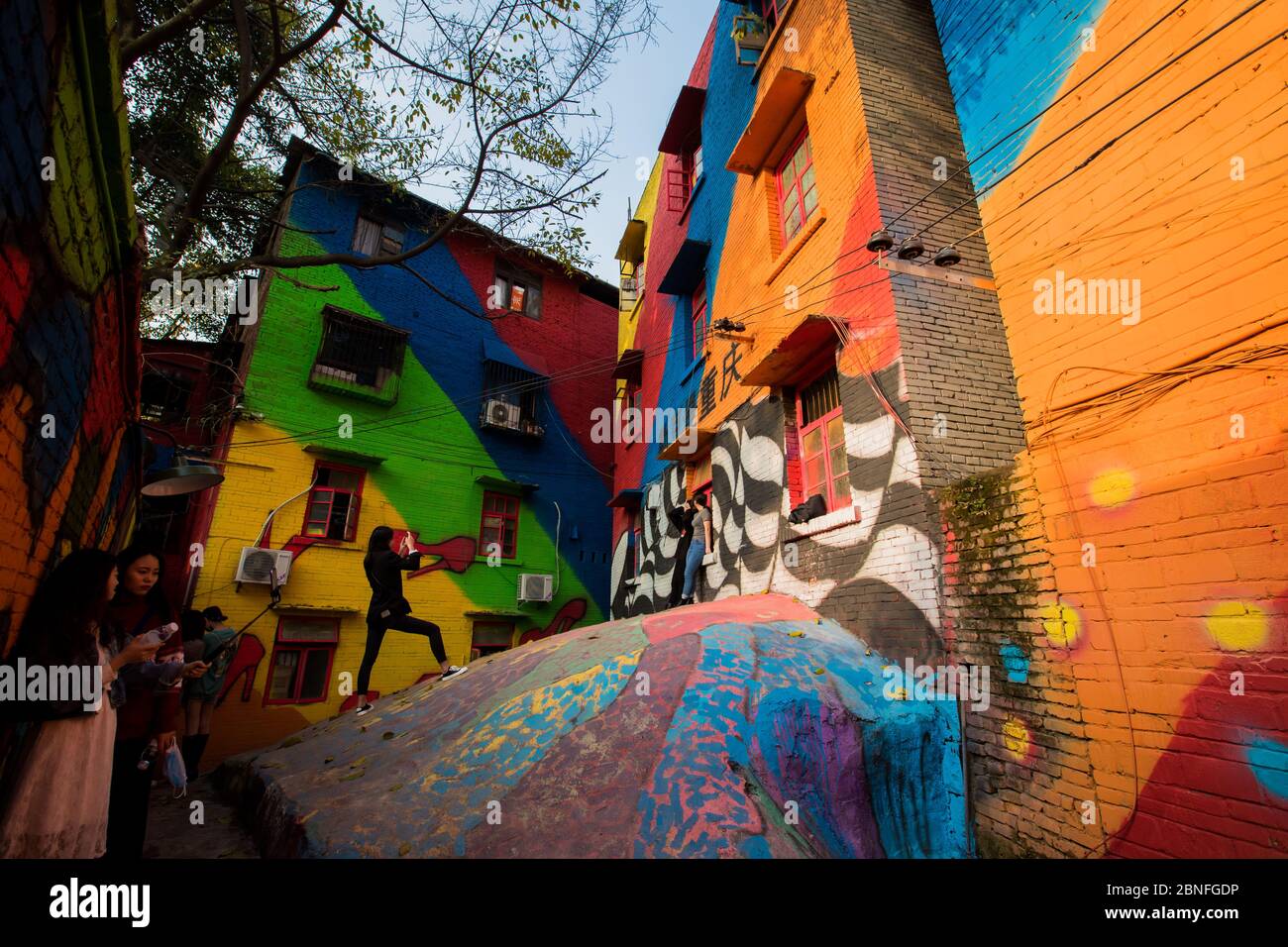 People take pictures against the colorful houses in Qicai Xiang, an old ...