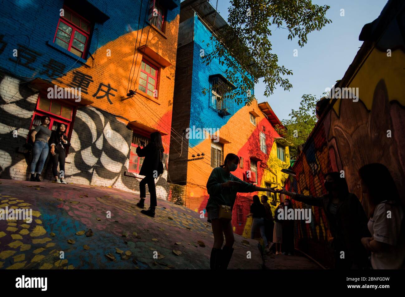 People take pictures against the colorful houses in Qicai Xiang, an old ...