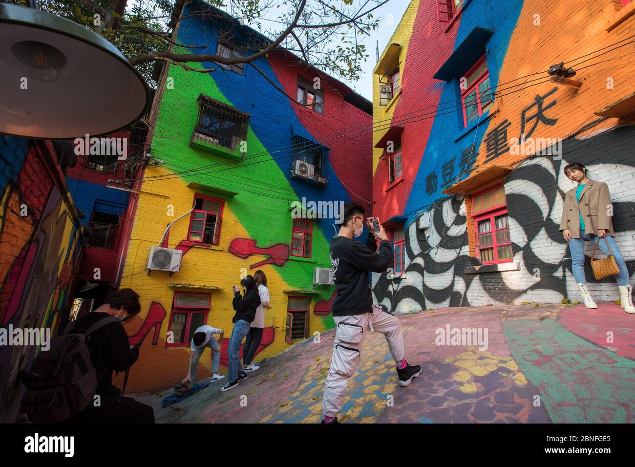 People take pictures against the colorful houses in Qicai Xiang, an old ...