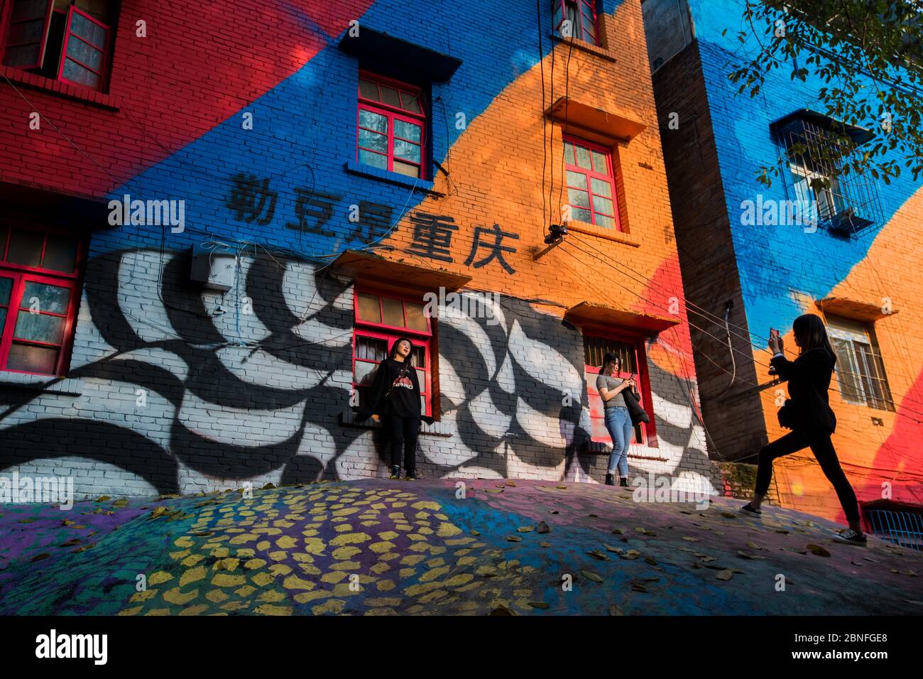 People take pictures against the colorful houses in Qicai Xiang, an old ...