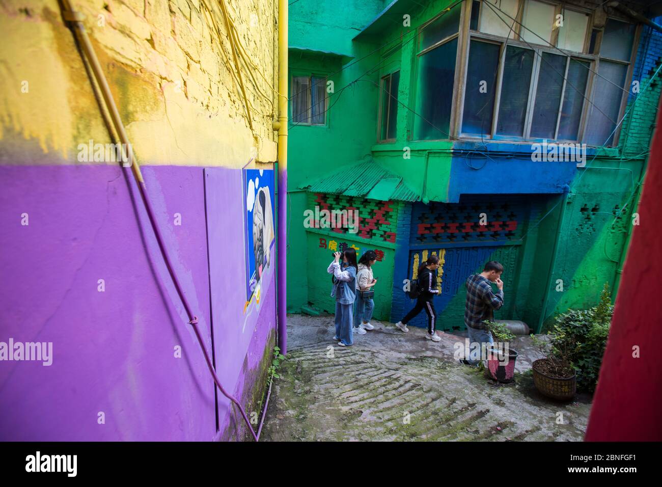 People take pictures against the colorful houses in Qicai Xiang, an old ...