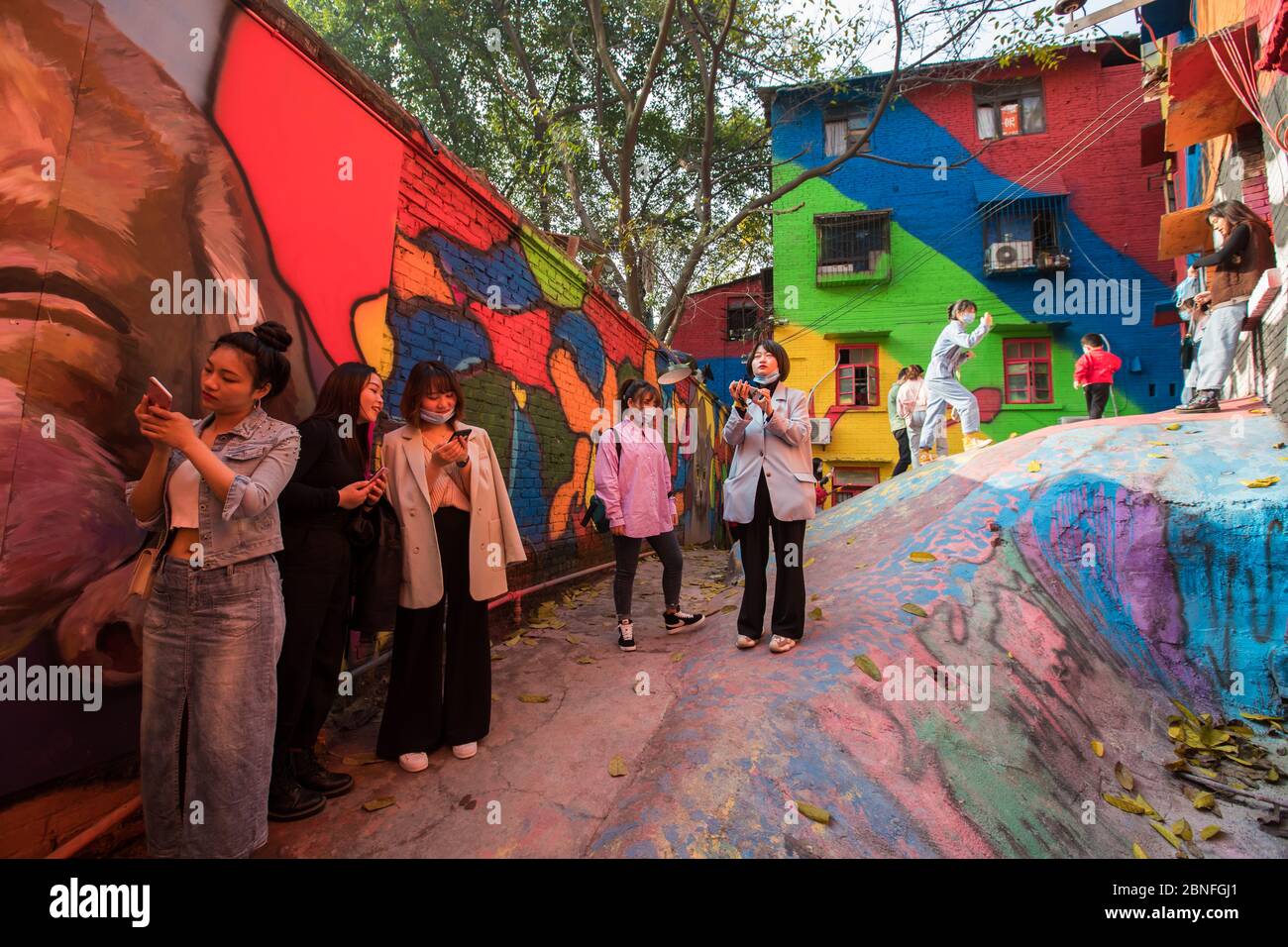 People take pictures against the colorful houses in Qicai Xiang, an old ...