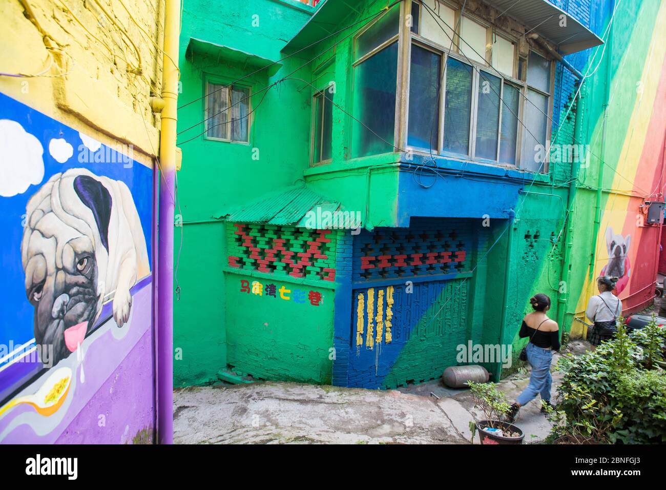 People take pictures against the colorful houses in Qicai Xiang, an old ...