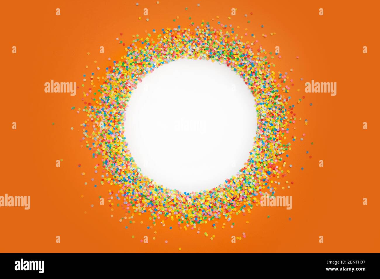 Round frame made of colored confetti. Orange background. Festive ...