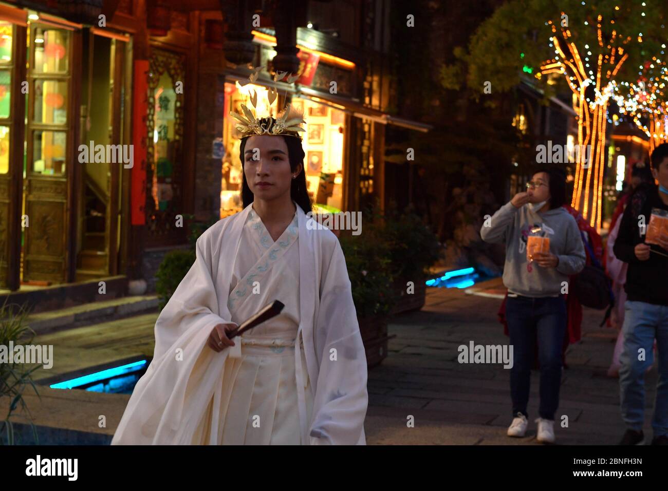 Tourists in ancient Chinese clothing walk along the street, on both of ...