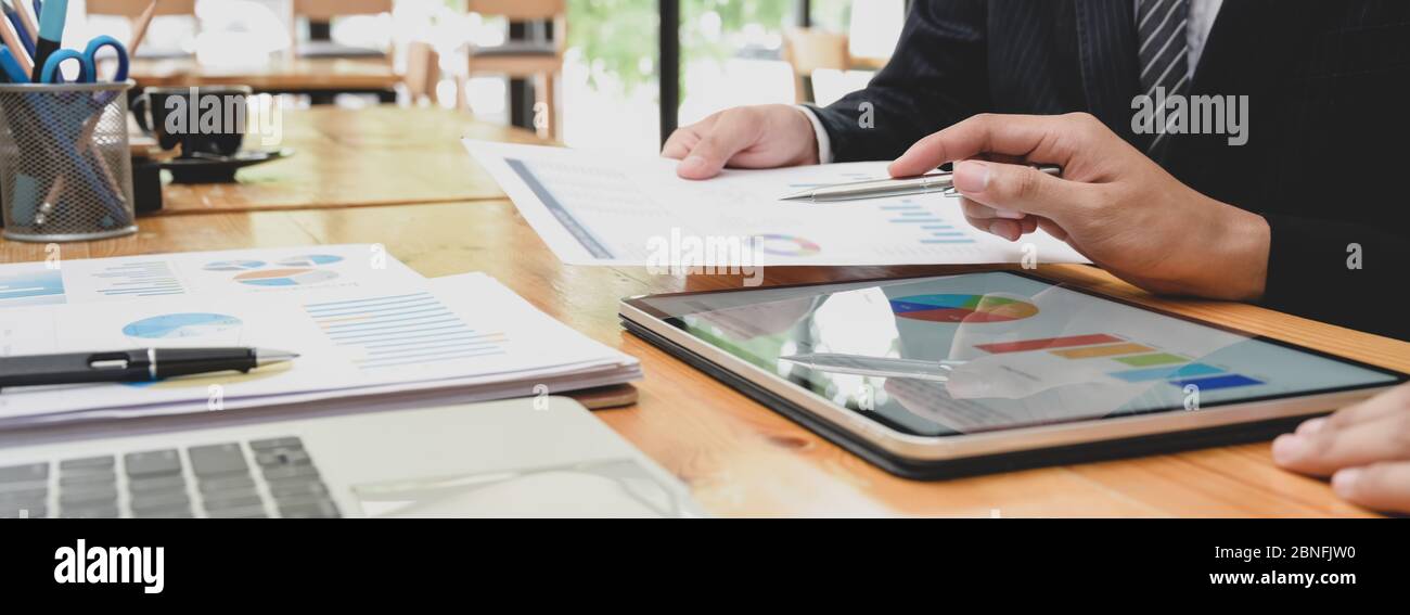 Side view of business partner analysing business chart on digital ...