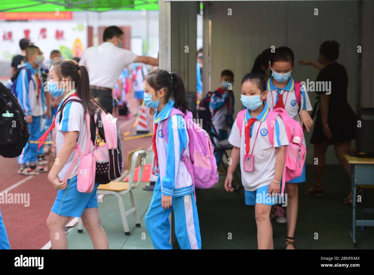 Students queue with a suitable distance under the guidance of a ...