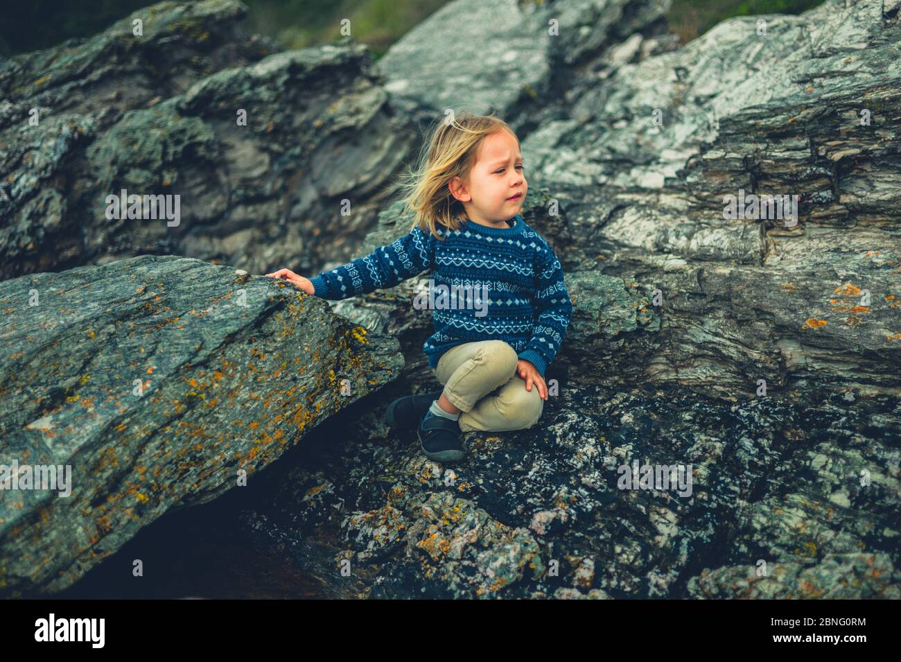 A little preschooler is sitting on the rocks in nature Stock Photo - Alamy