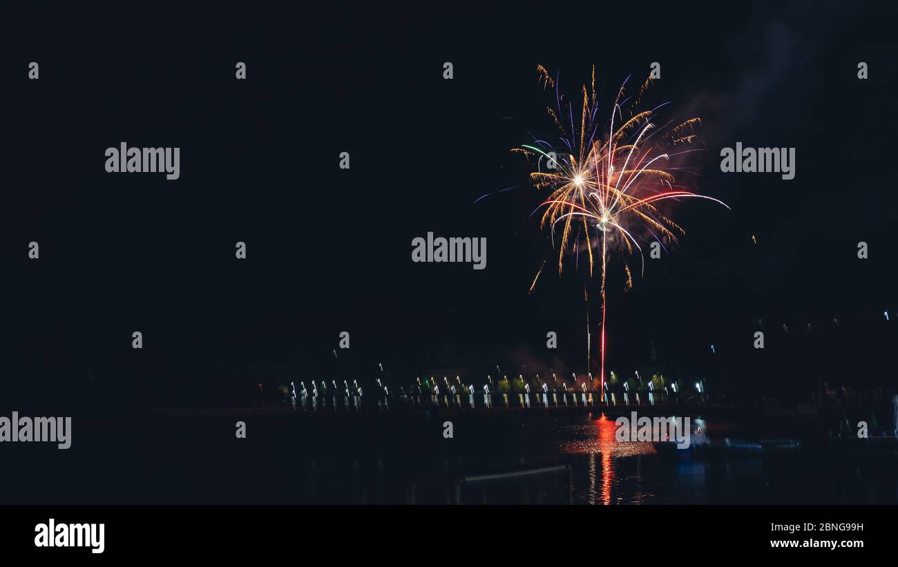 Panoramic shot of colorful fireworks above a city with lights at night ...