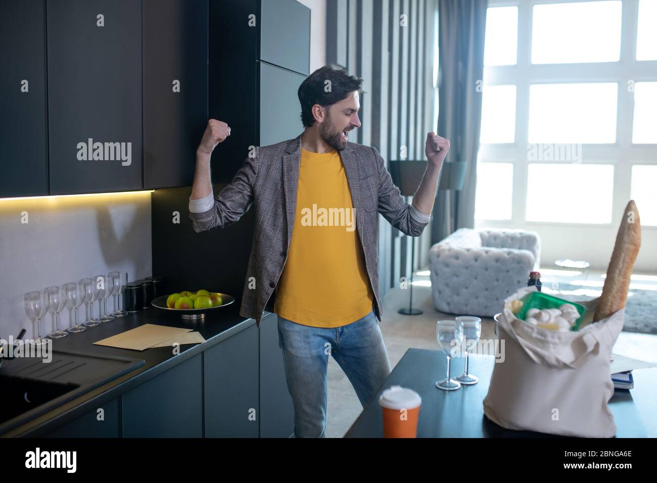 Young dark-haired man rejoicing at home in the kitchen Stock Photo - Alamy