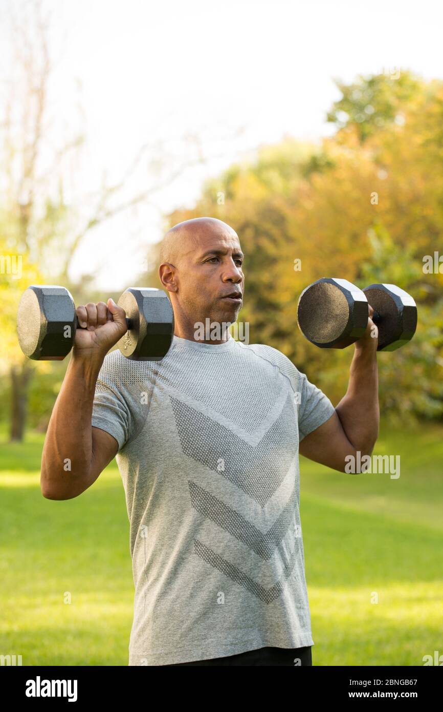 Fit African American man lifting weights outside Stock Photo - Alamy