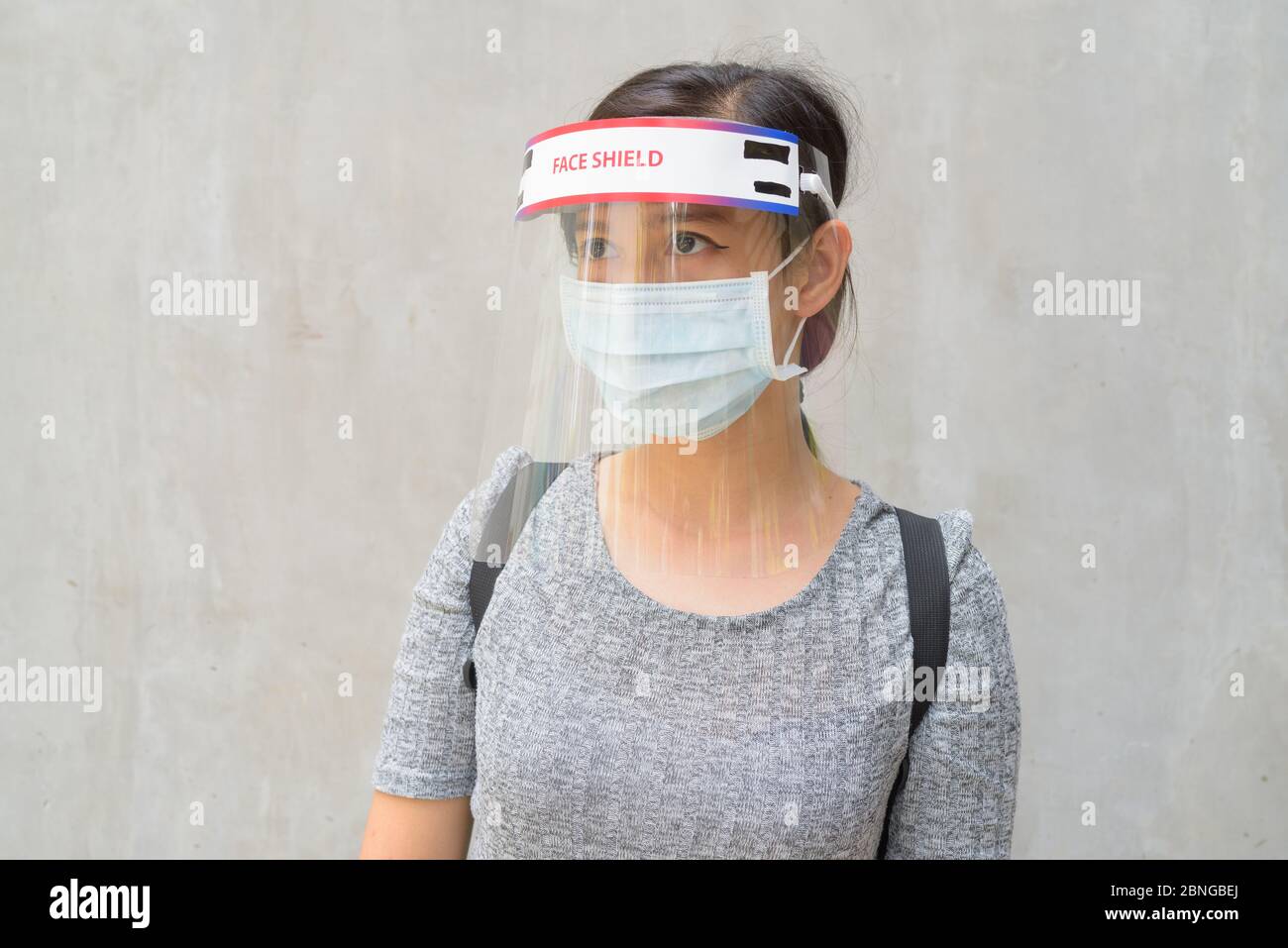 Young Asian woman thinking with mask and face shield for protection ...