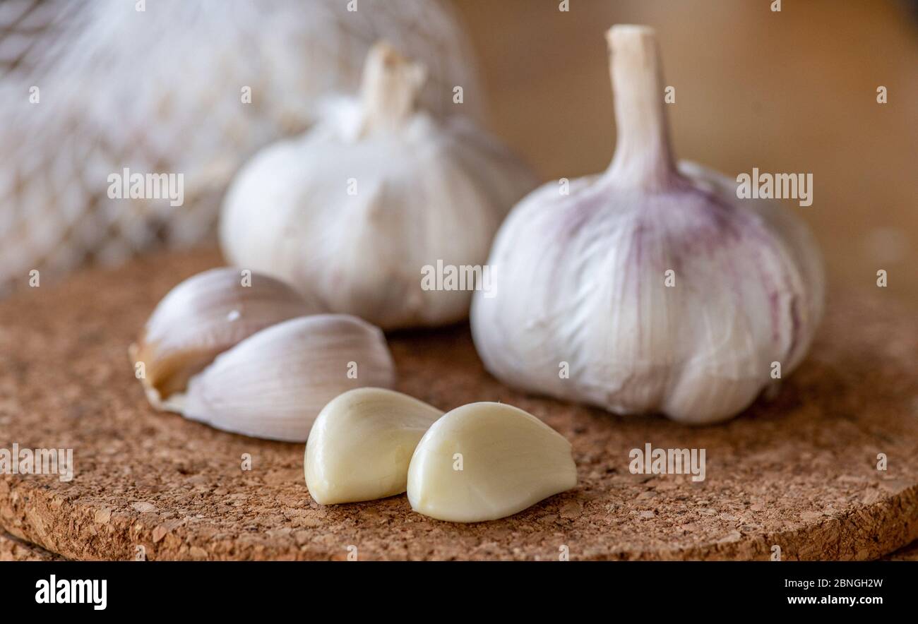 Closeup of garlic bulb and cloves on a round cork board Stock Photo - Alamy