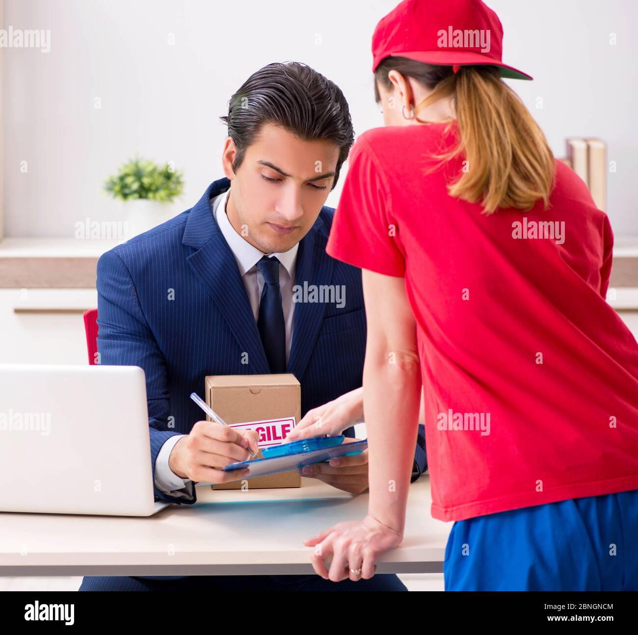 The courier delivering parcel to the office Stock Photo - Alamy