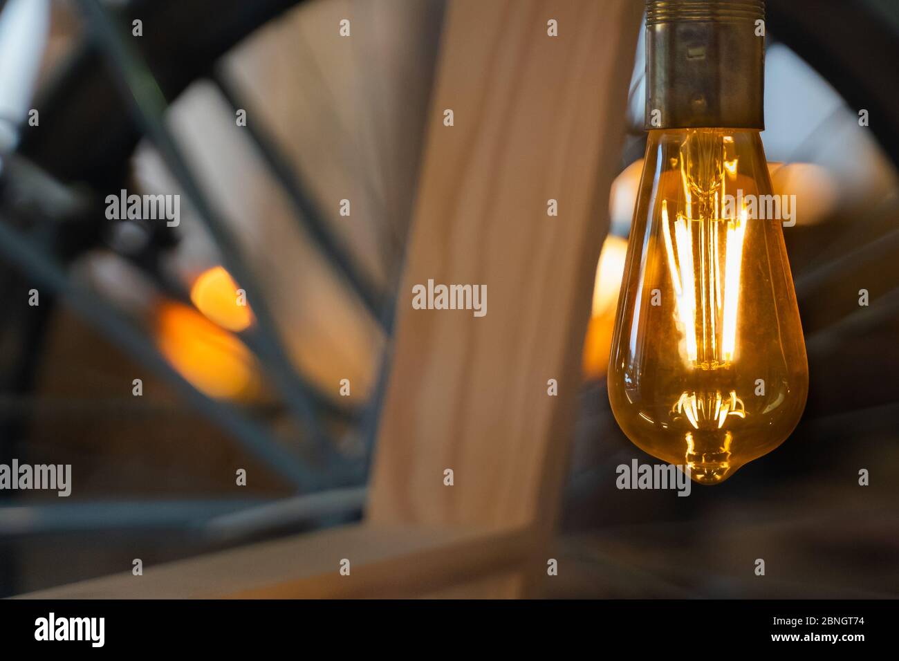 decorative edison style light bulb against wooden stairs and bicycle ...