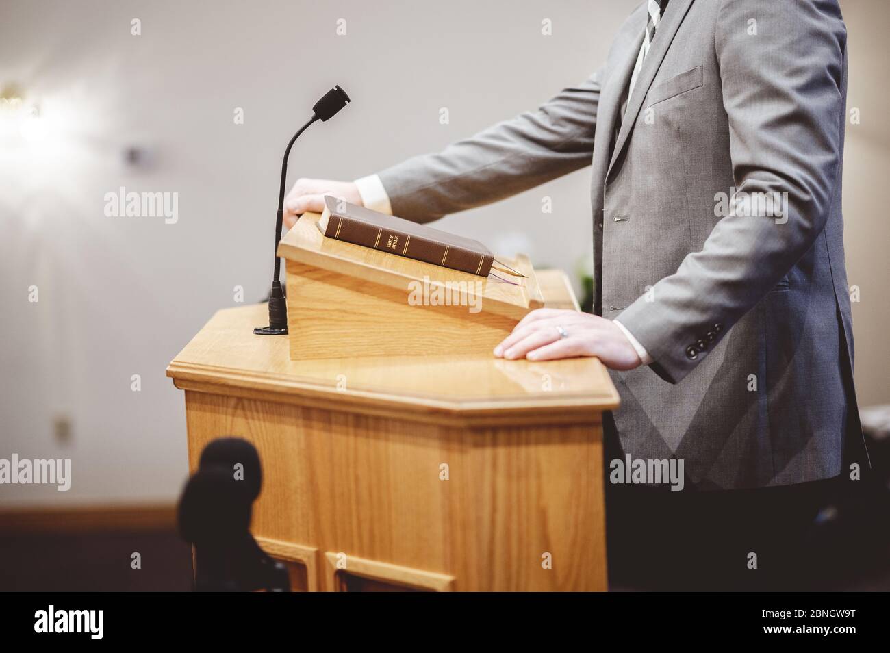Selective focus shot of a male standing and speaking from the pulpit ...