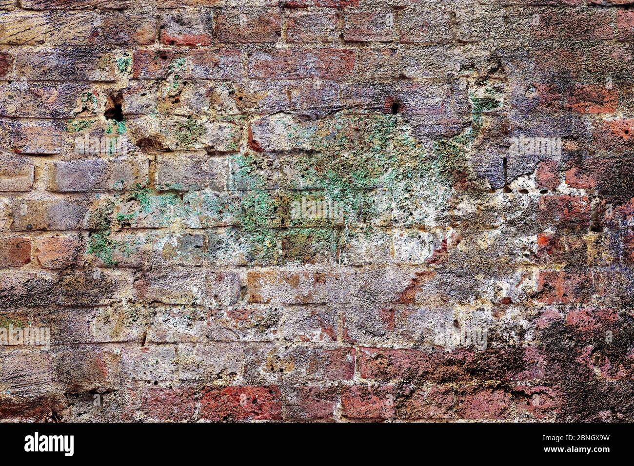 View of an old wall made of bricks and partially covered with cement ...