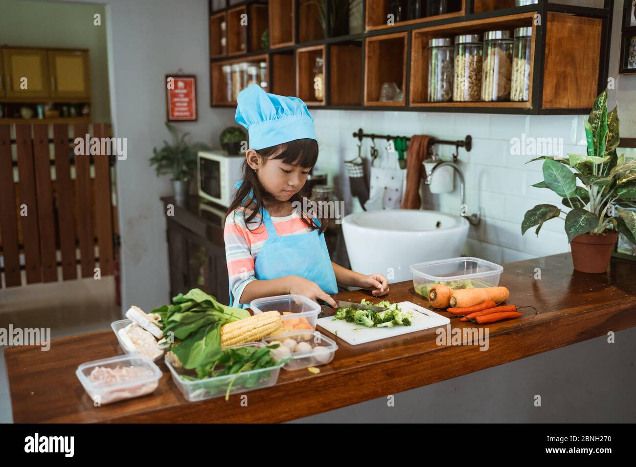 asian kid with apron cooking in the kitchen Stock Photo - Alamy