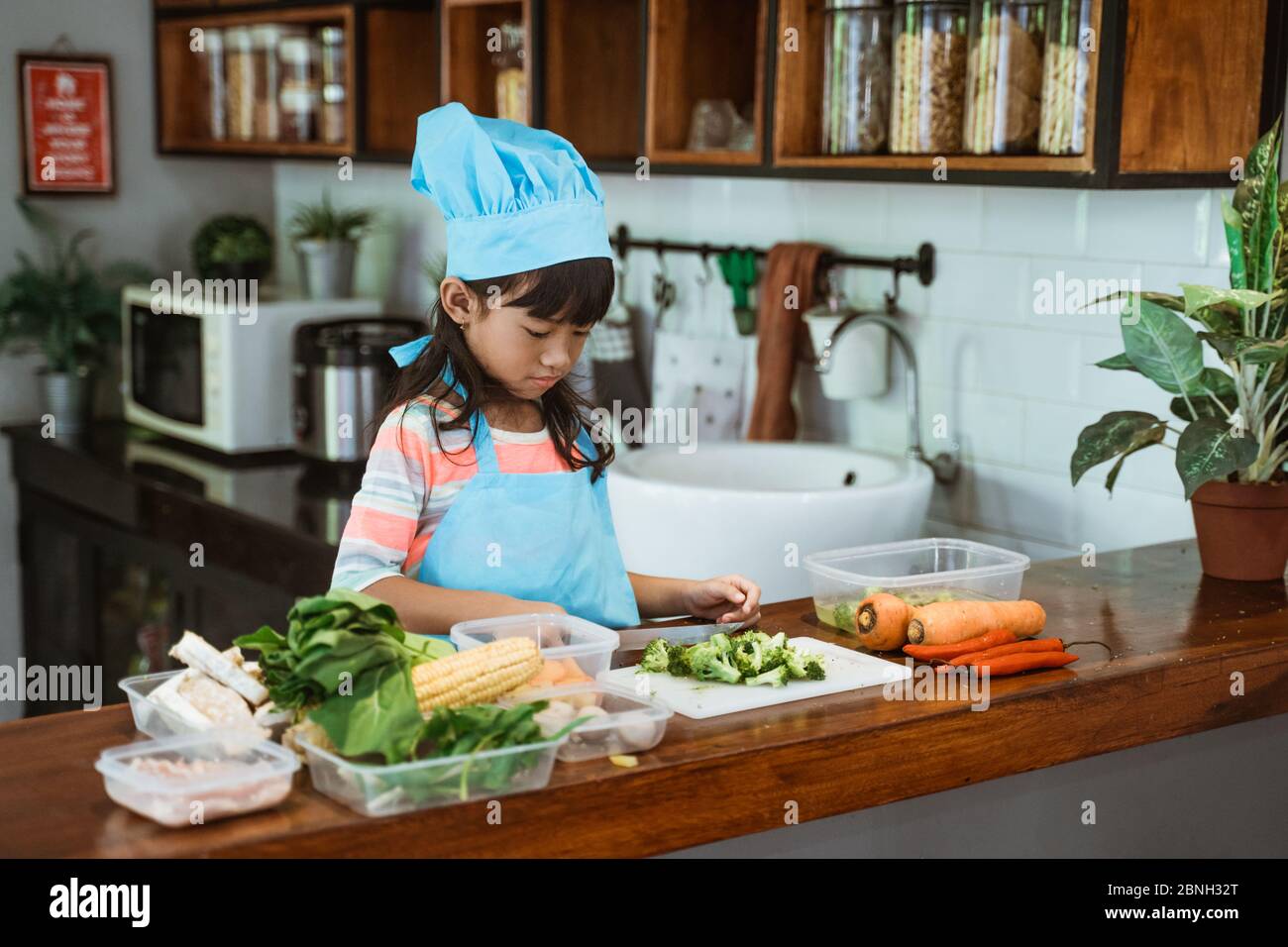 asian kid with apron cooking in the kitchen Stock Photo - Alamy