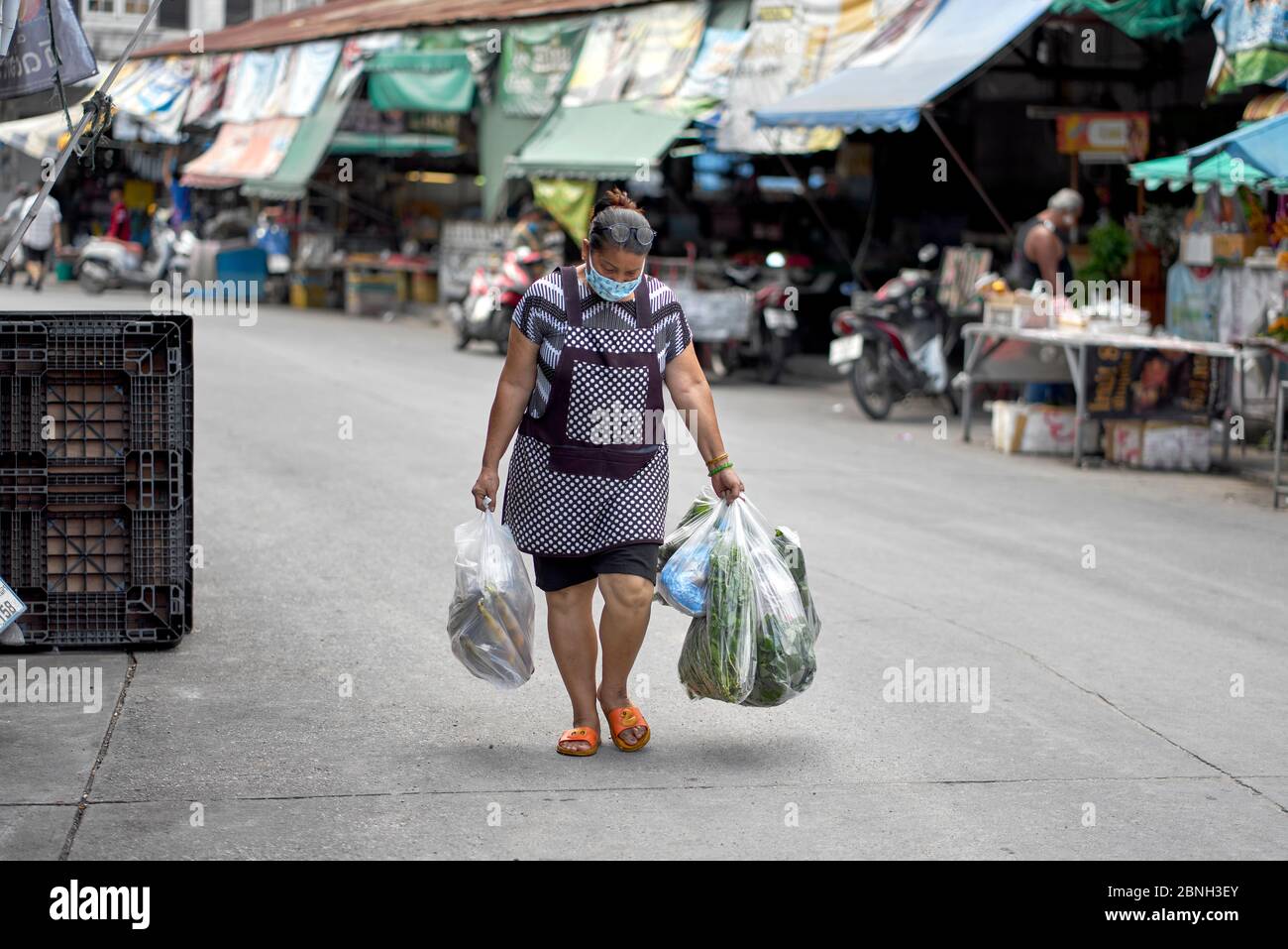 COVID-19 effect. Woman returning from a food shopping trip amidst the deserted streets of a once ...