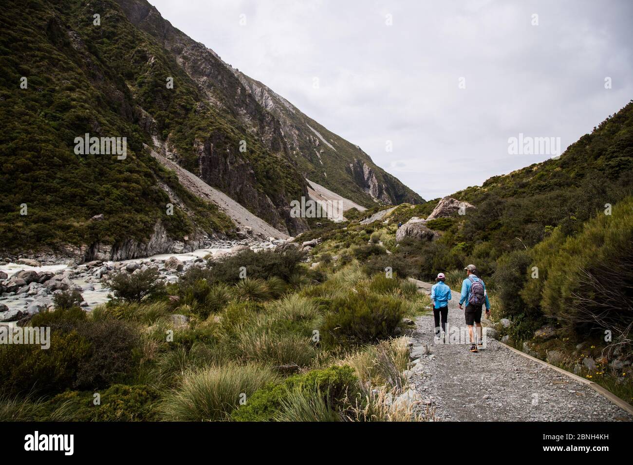 View of two people hiking in the tree-covered cliffs with a river ...