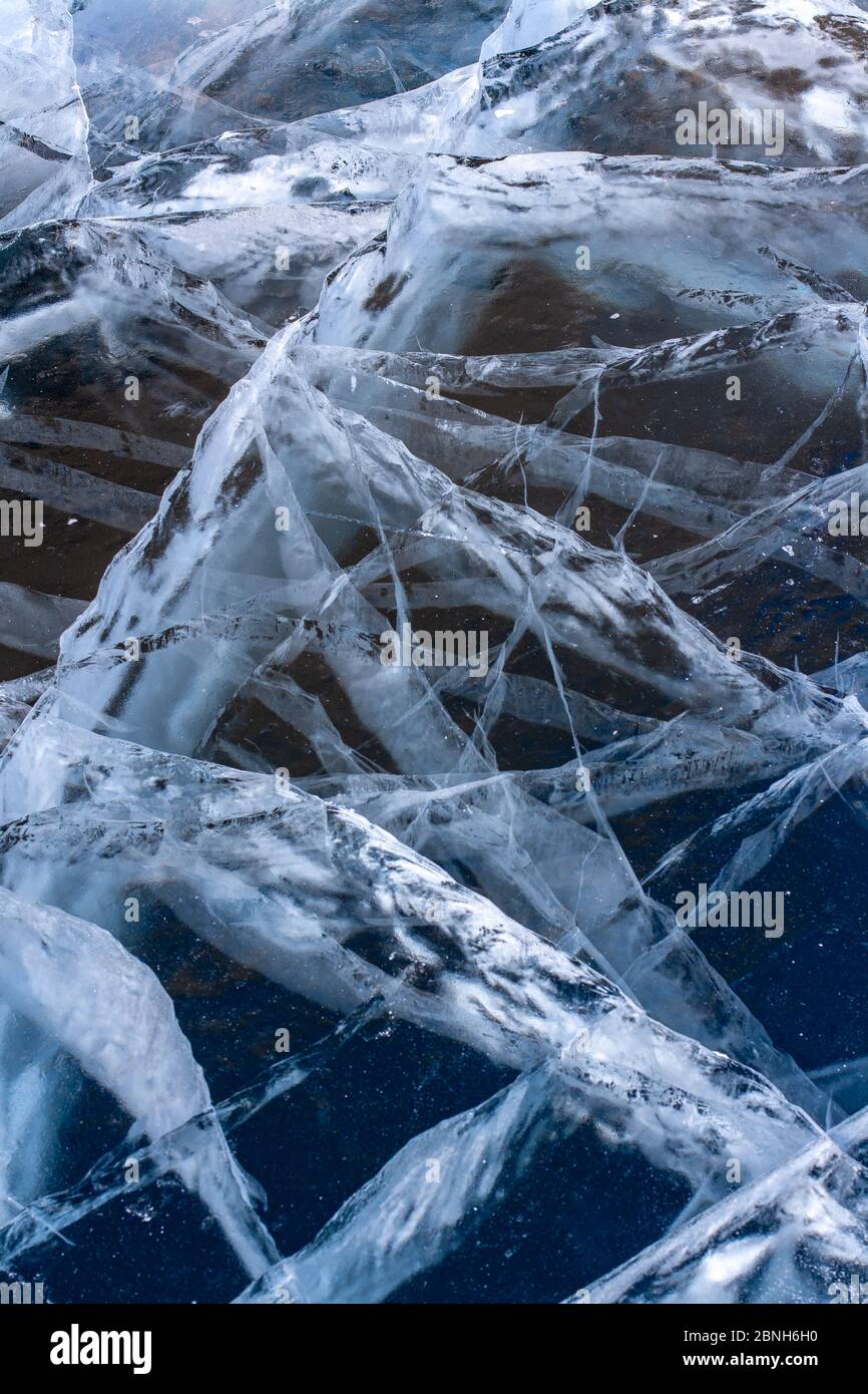 Cracked thick ice on the lake. Many deep and shallow cracks in clear ...
