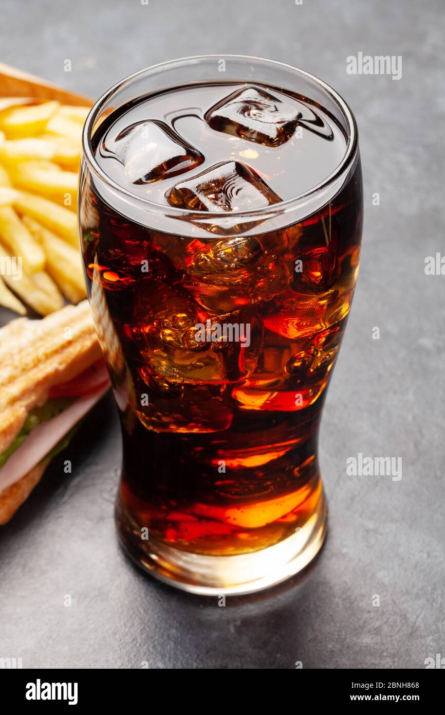 Glass of cola drink with ice, club sandwich and potato fries chips ...
