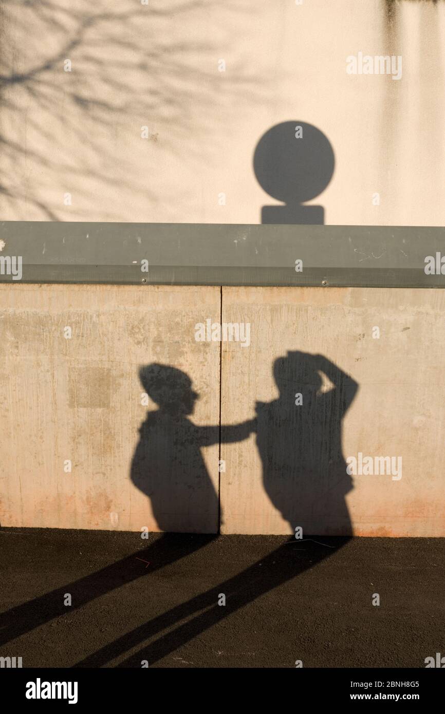 silhouetted shadows of two young pupils, waiting for school to open, on ...