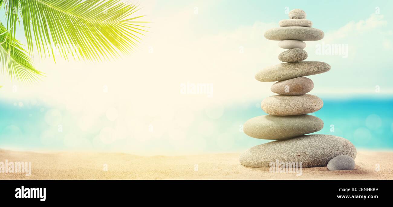 Pyramid of sea pebbles on a sunny sand beach. Life balance and harmony ...