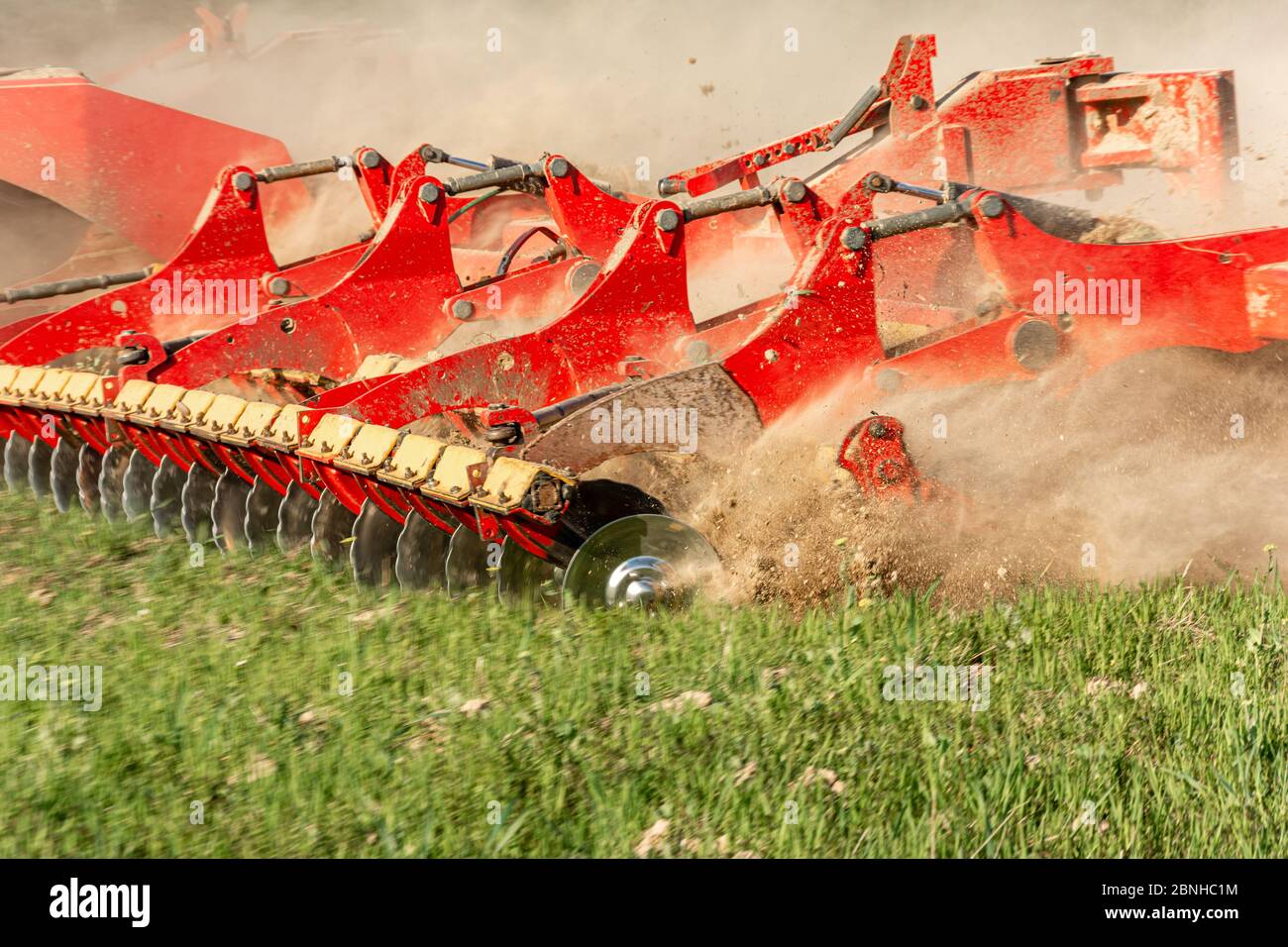 Agricultural equipment shreds the plowed land. A crawler tractor pulls ...