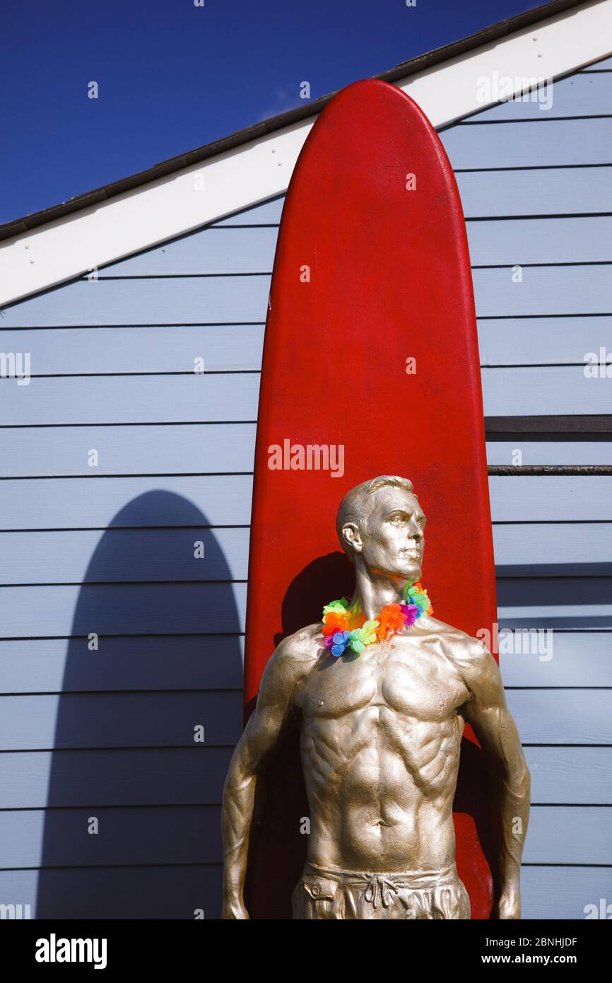 Statue of a golden waterman surfer with a red longboard surfboard Stock ...
