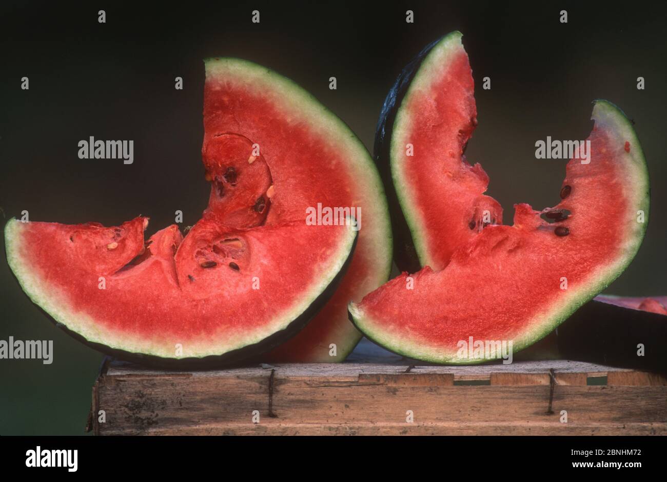 View of sliced ripe watermelons on a wooden surface with a black ...