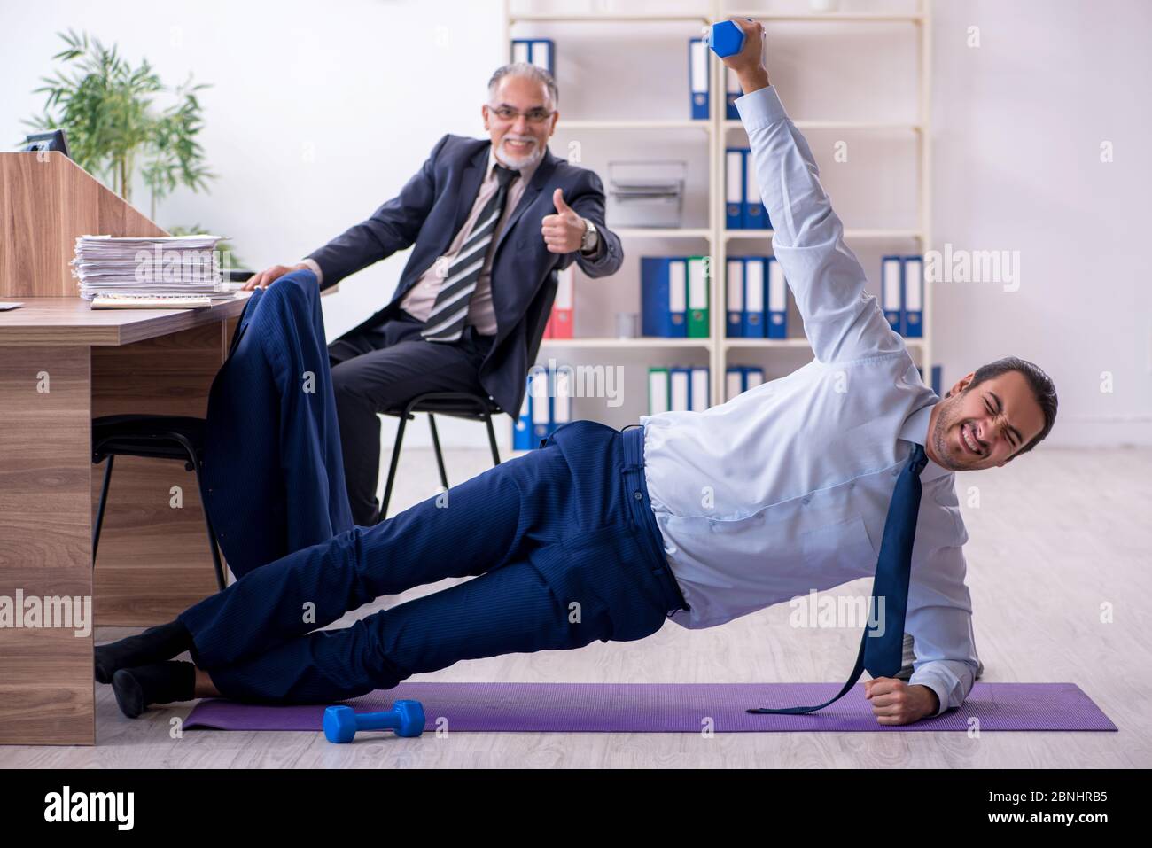 Two employees doing physical exercises at the workplace Stock Photo - Alamy