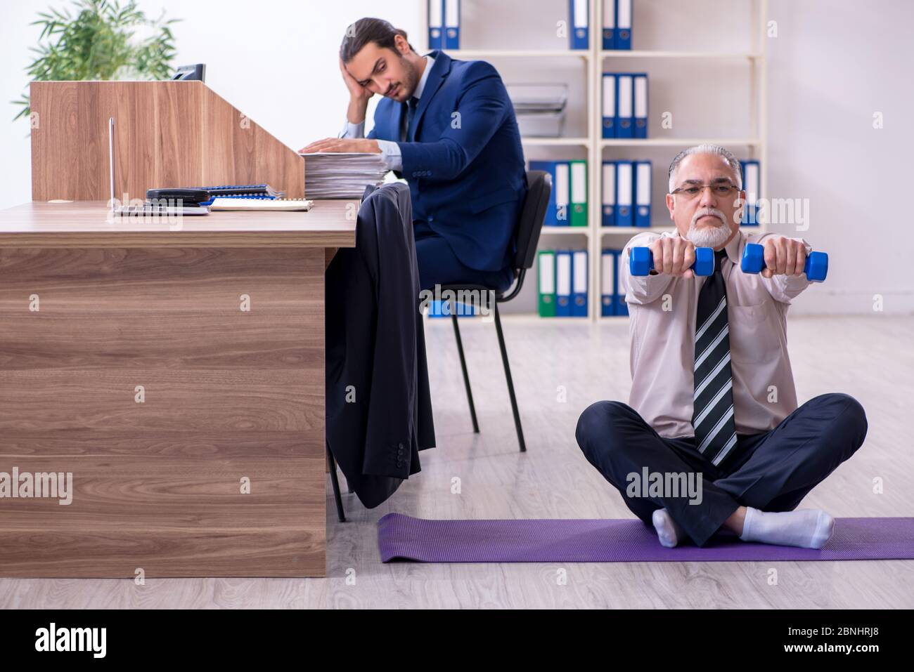 Two employees doing physical exercises at the workplace Stock Photo - Alamy