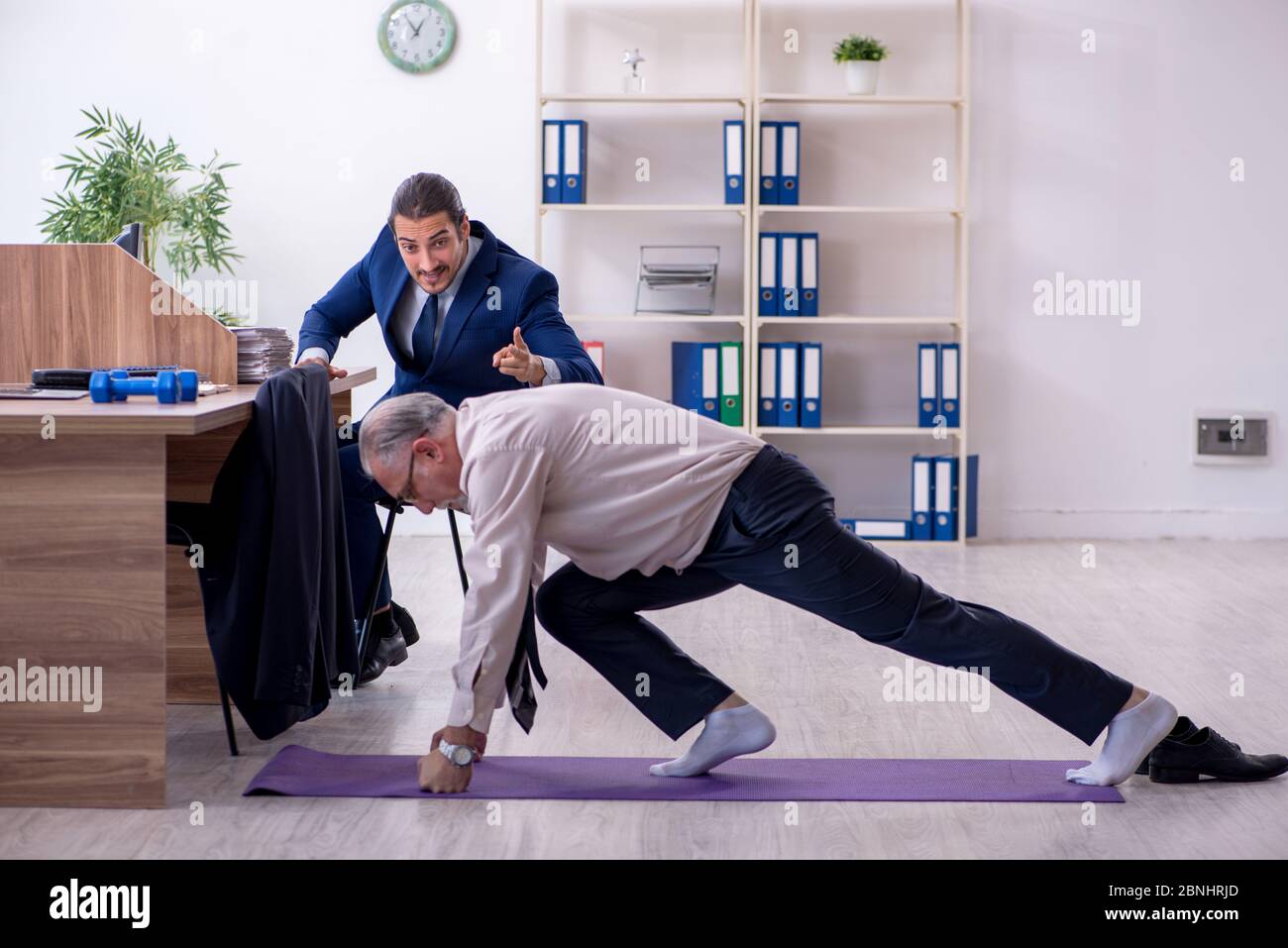 Two employees doing physical exercises at the workplace Stock Photo - Alamy