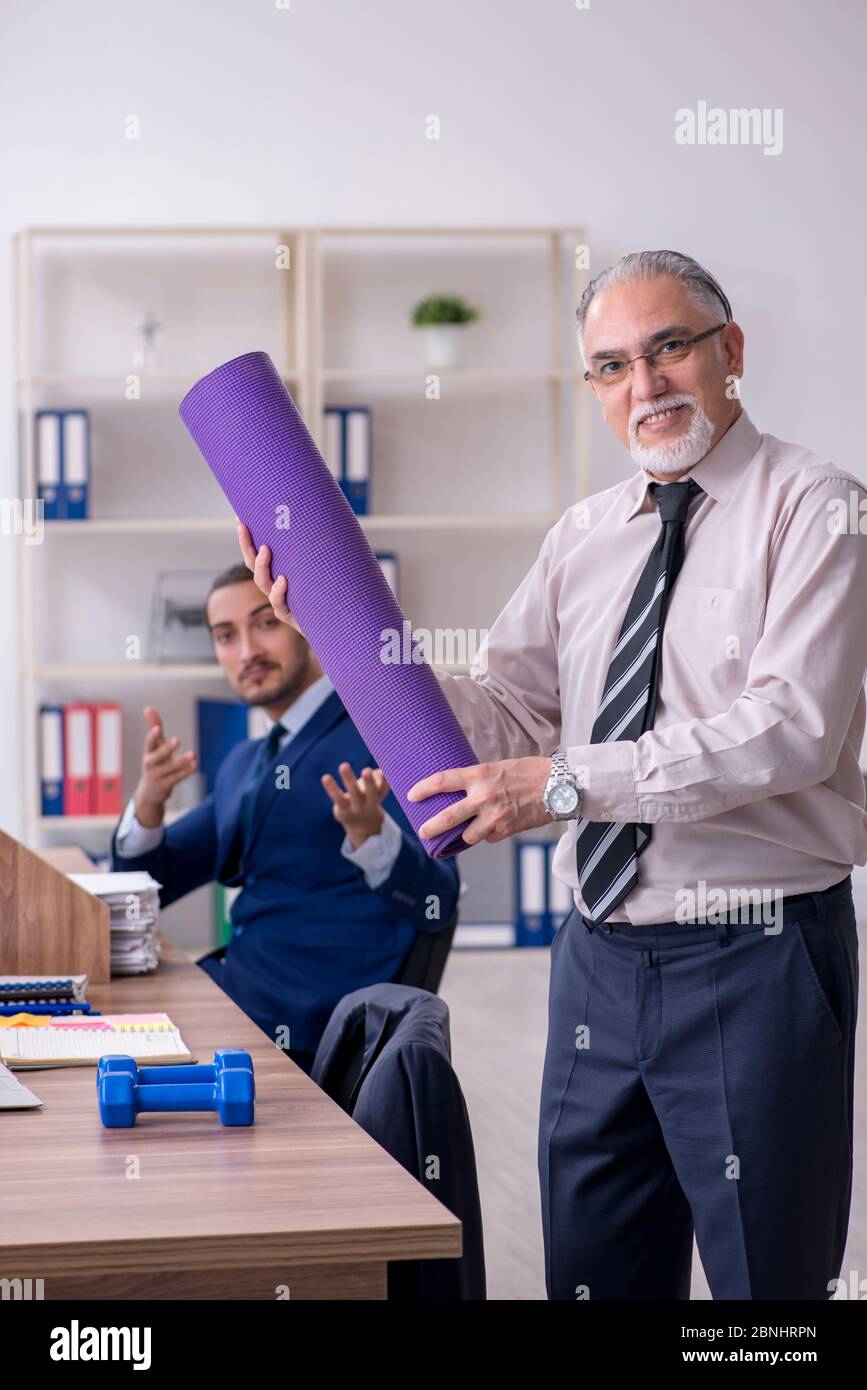 Two employees doing physical exercises at the workplace Stock Photo - Alamy