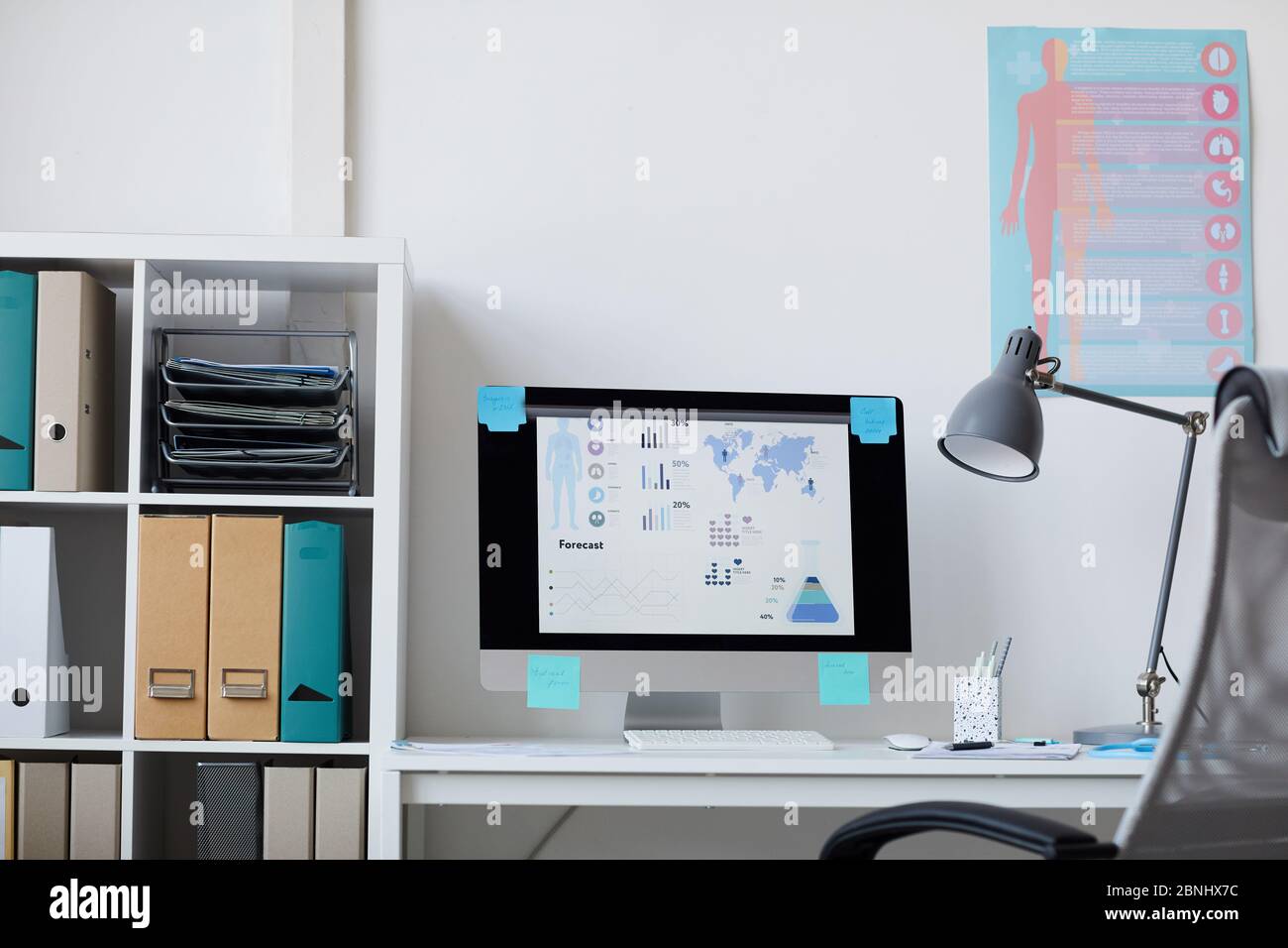 Image of workplace with computer monitor on it and medical posters on ...