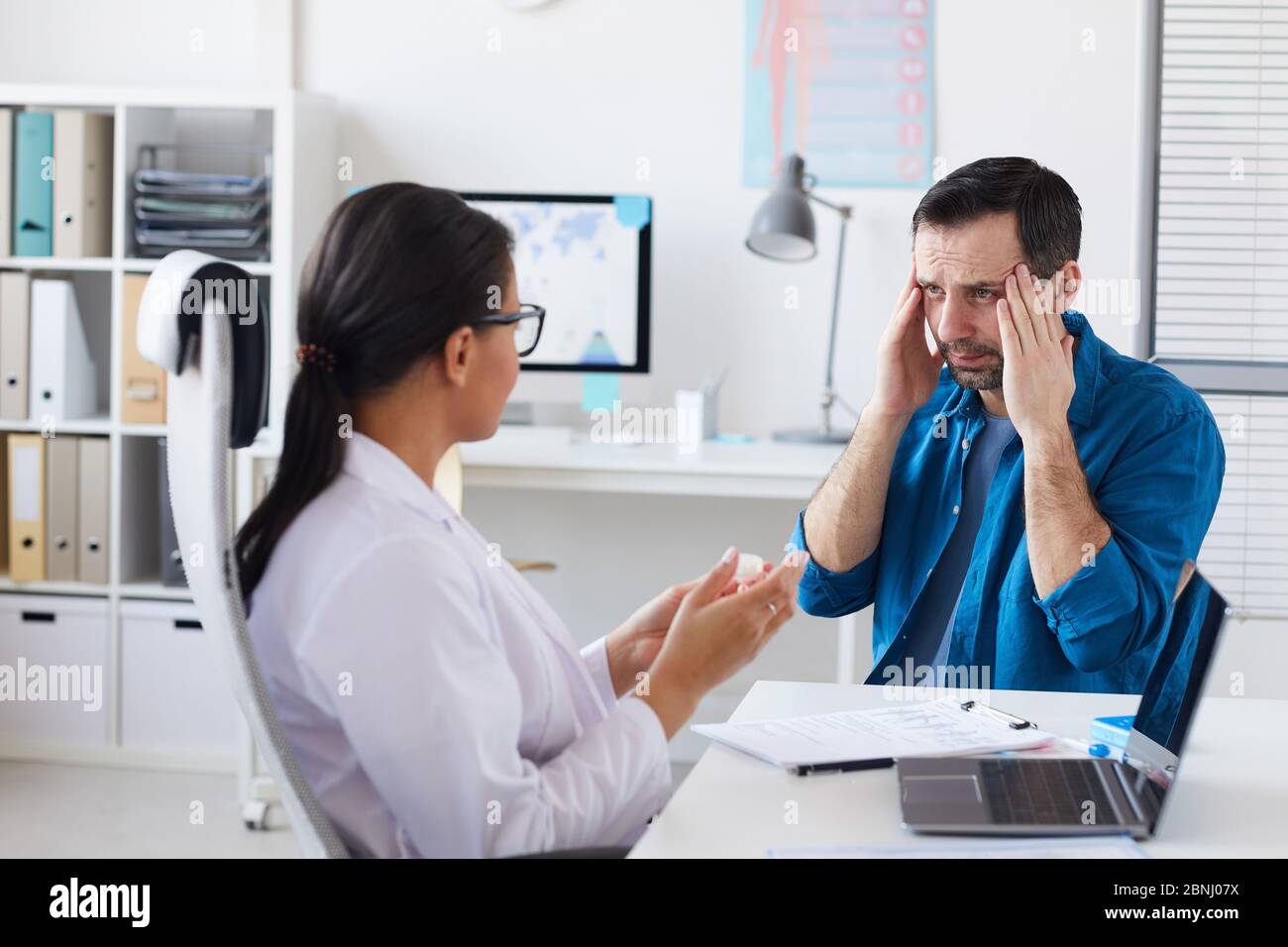 Patient complaining on headache during his visit to the doctor while ...