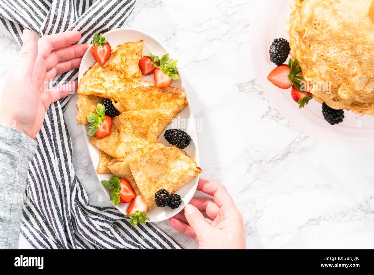 Flat lay. Freshly baked crepes folded in triangles and garnished with ...