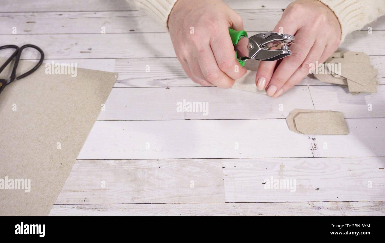Step by step. Cutting out gift tags from brown paper with a paper punch ...